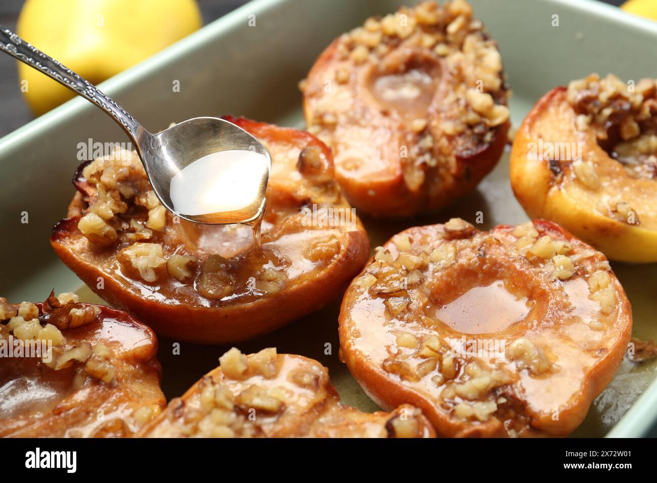 Pouring honey onto tasty baked quinces with nuts in dish, closeup Stock ...