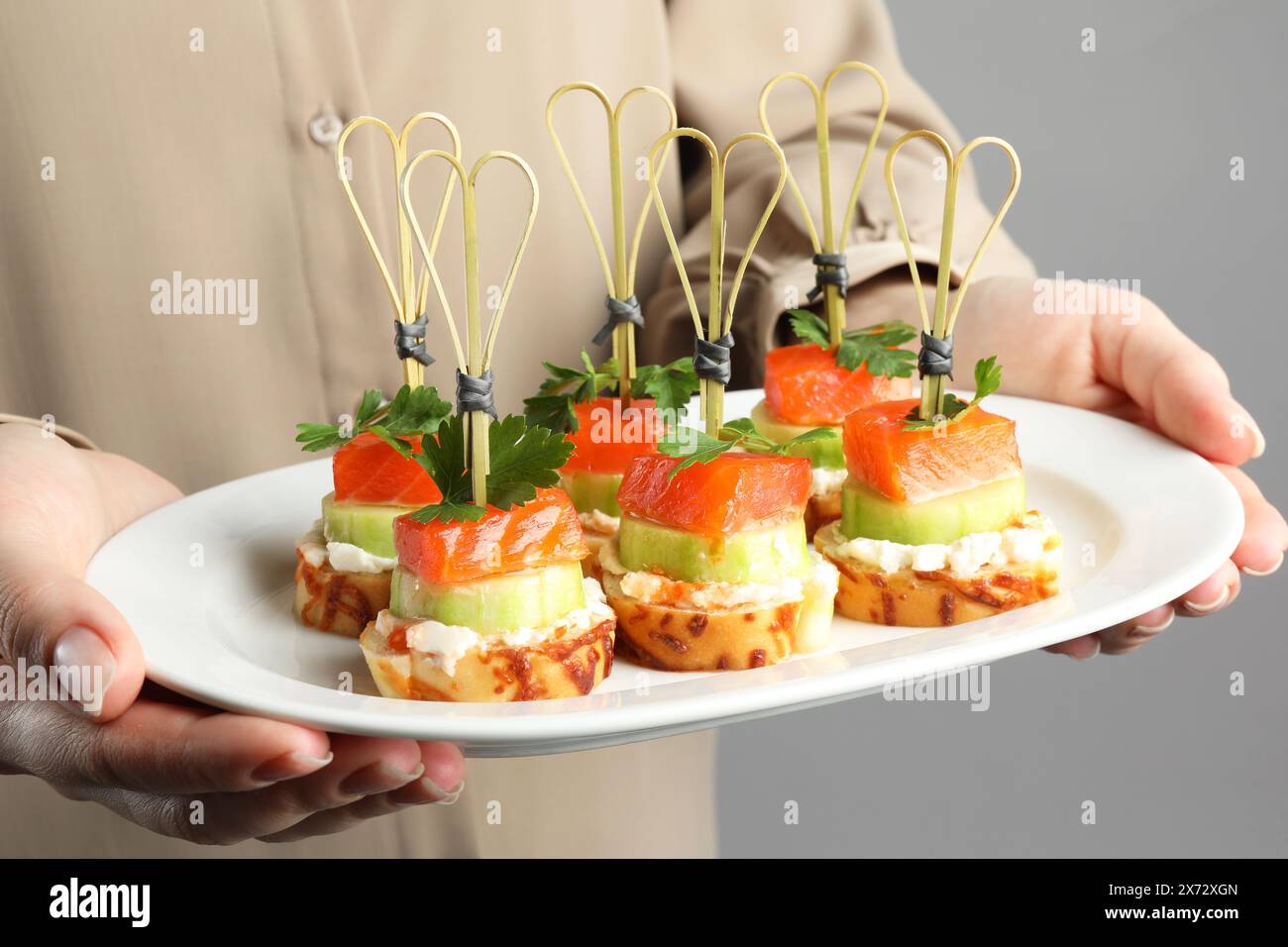 Woman holding tasty canapes with salmon, cucumber, bread and cream ...
