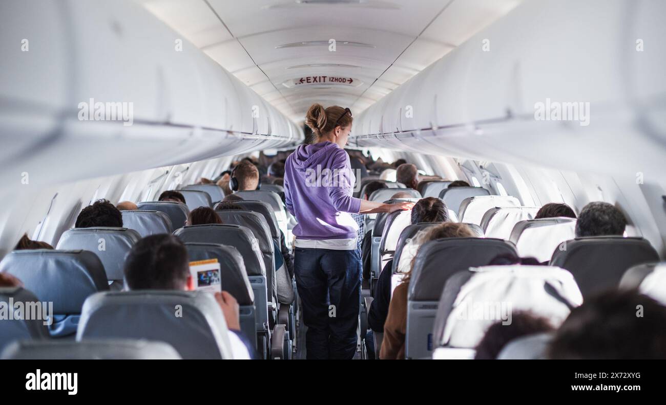 Interior of airplane with passengers on seats and female traveler ...