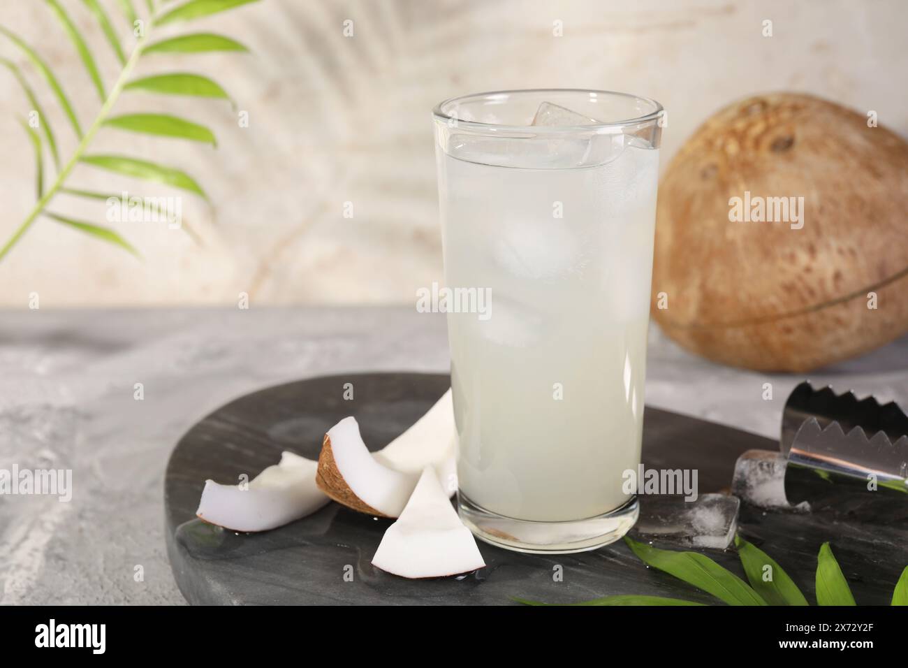 Glass of coconut water, ice cubes and nuts on grey table Stock Photo ...