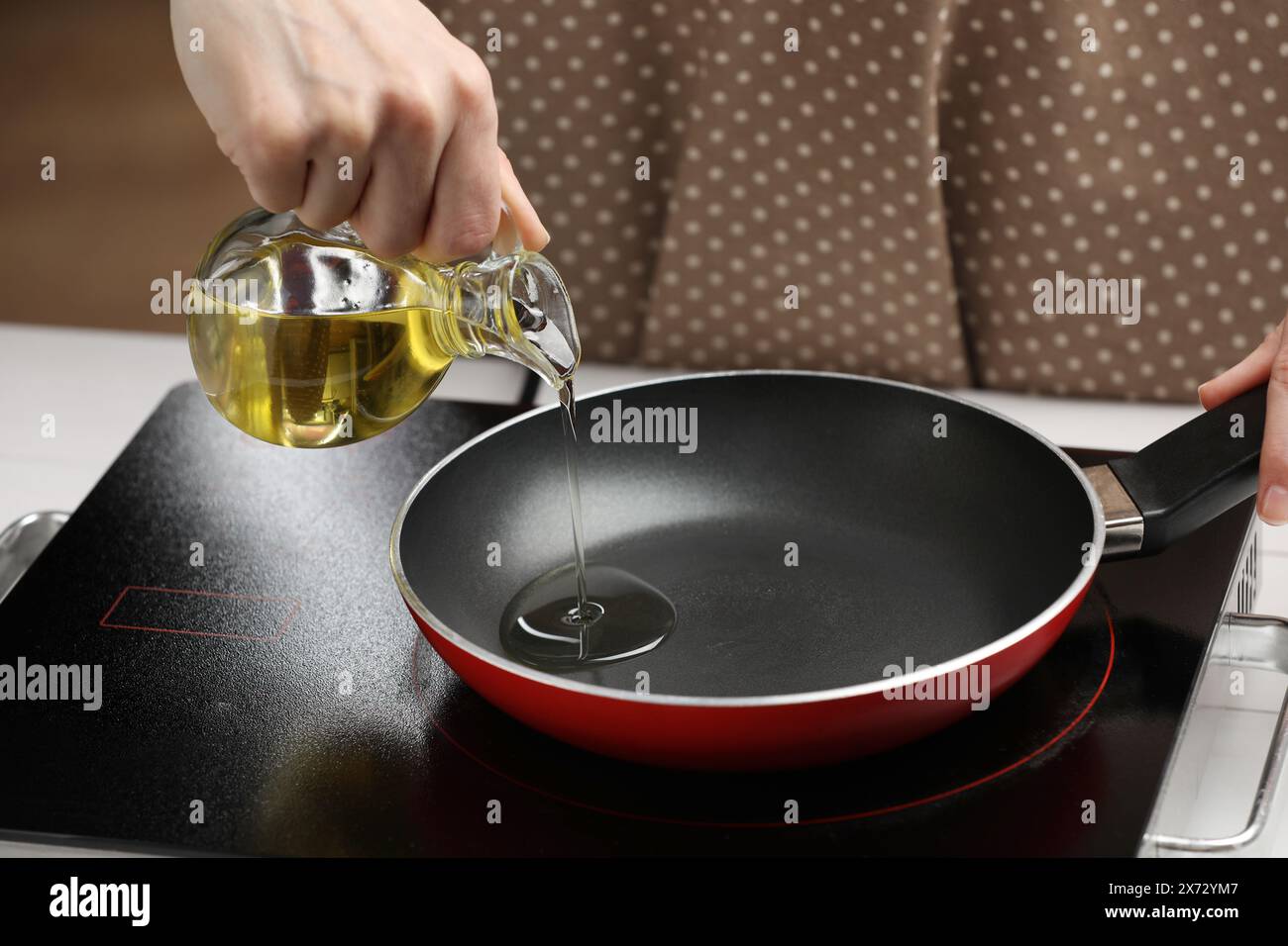 Vegetable fats. Woman pouring cooking oil into frying pan on stove ...