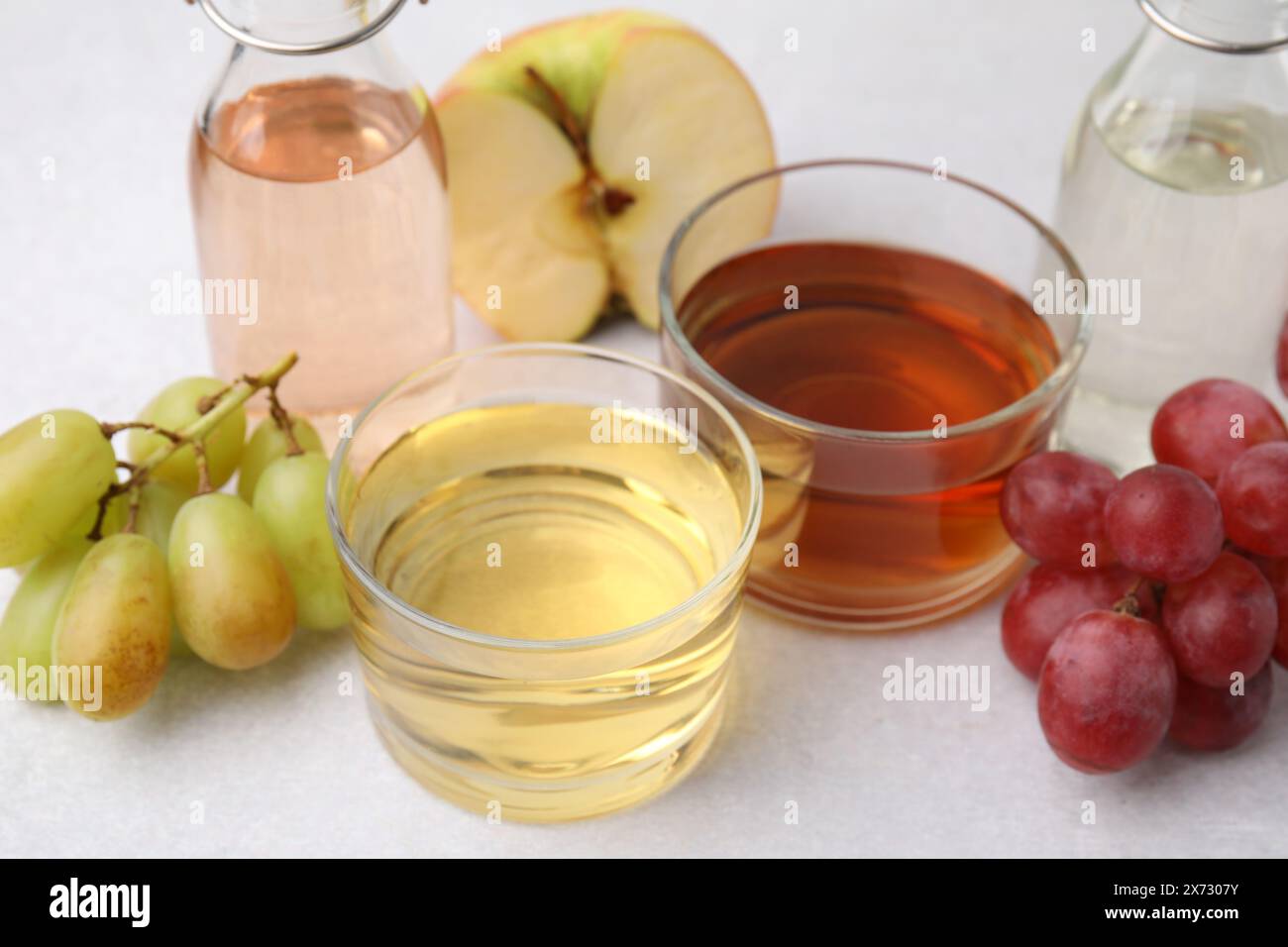 Different types of vinegar and ingredients on light table, closeup ...