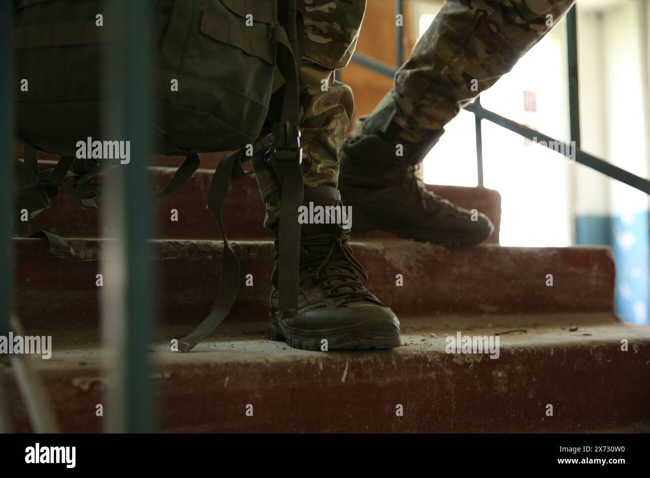 Military mission. Soldier in uniform on stairs inside abandoned ...