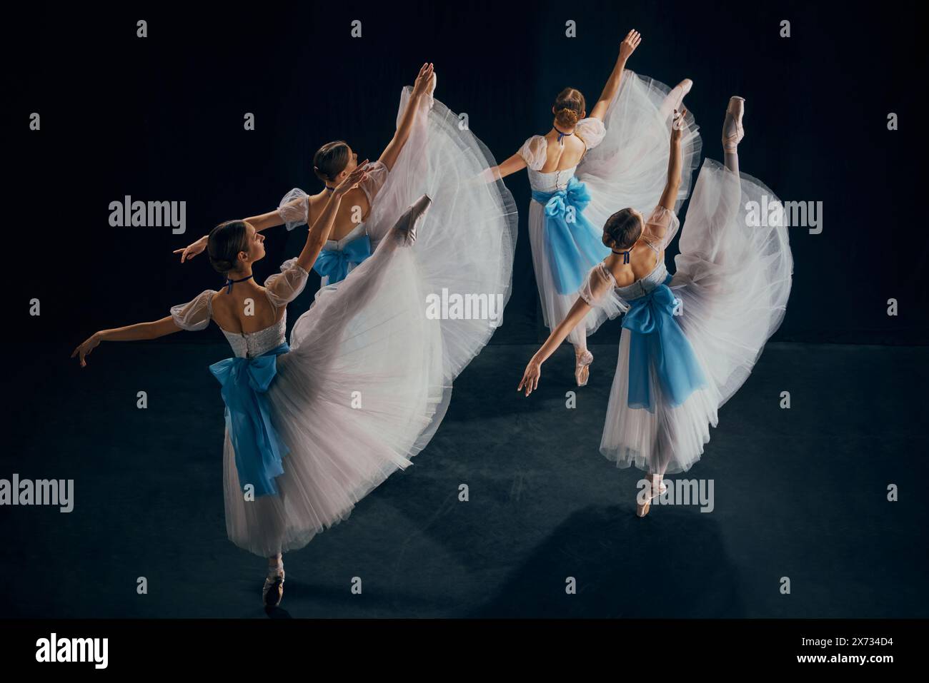 Four ballerinas in white and blue costumes performing on stage, each ...