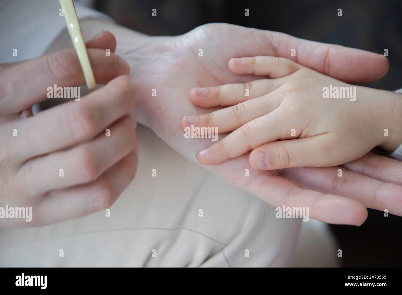 Close-up of an adult carefully trimming a child's fingernails ...