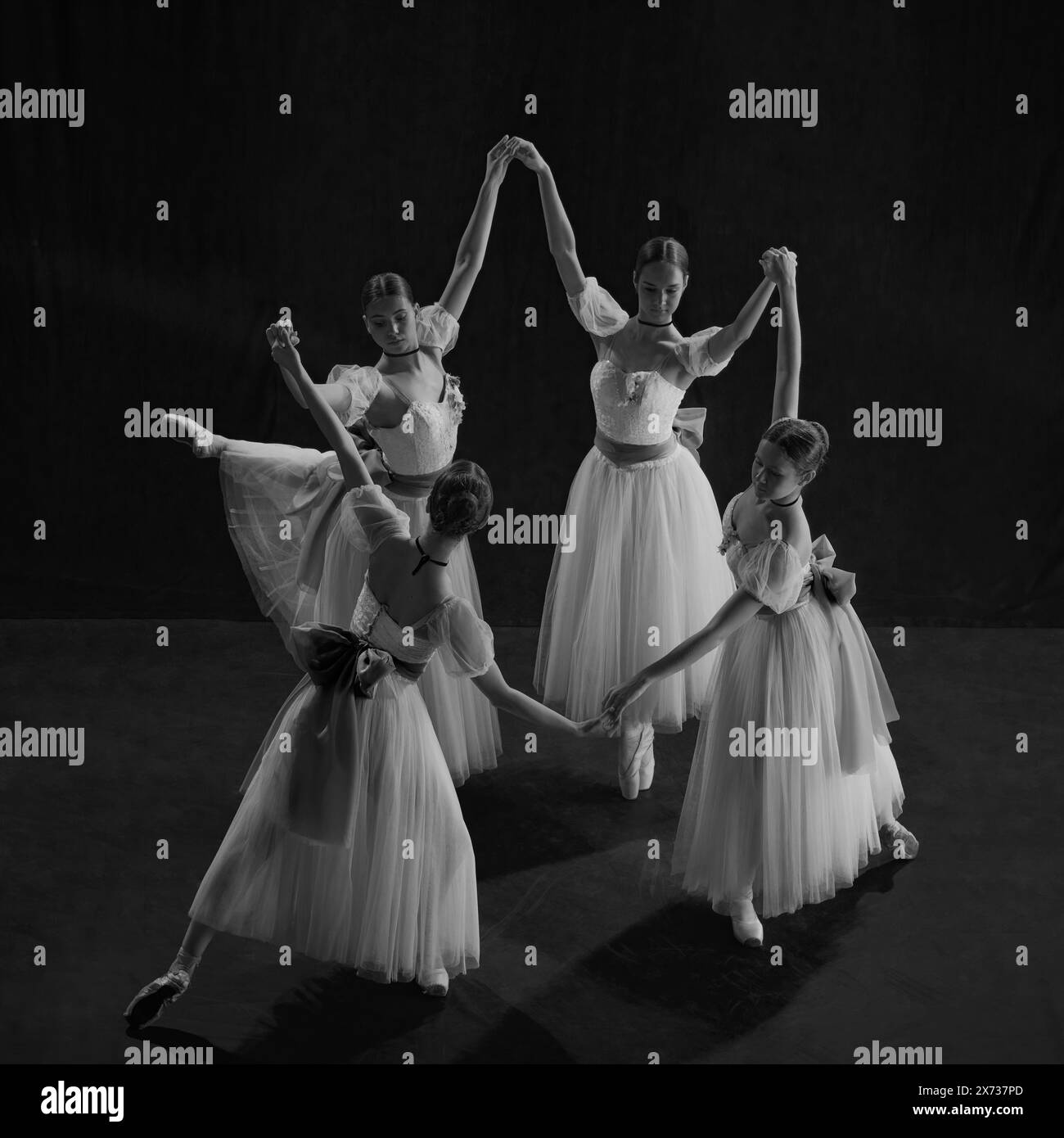 Four ballerinas hold hands as they perform delicate ballet pose race ...