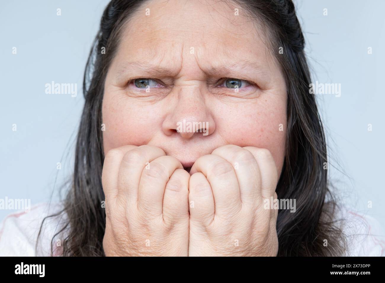 distressed mature woman with long hair nervously biting her nails ...