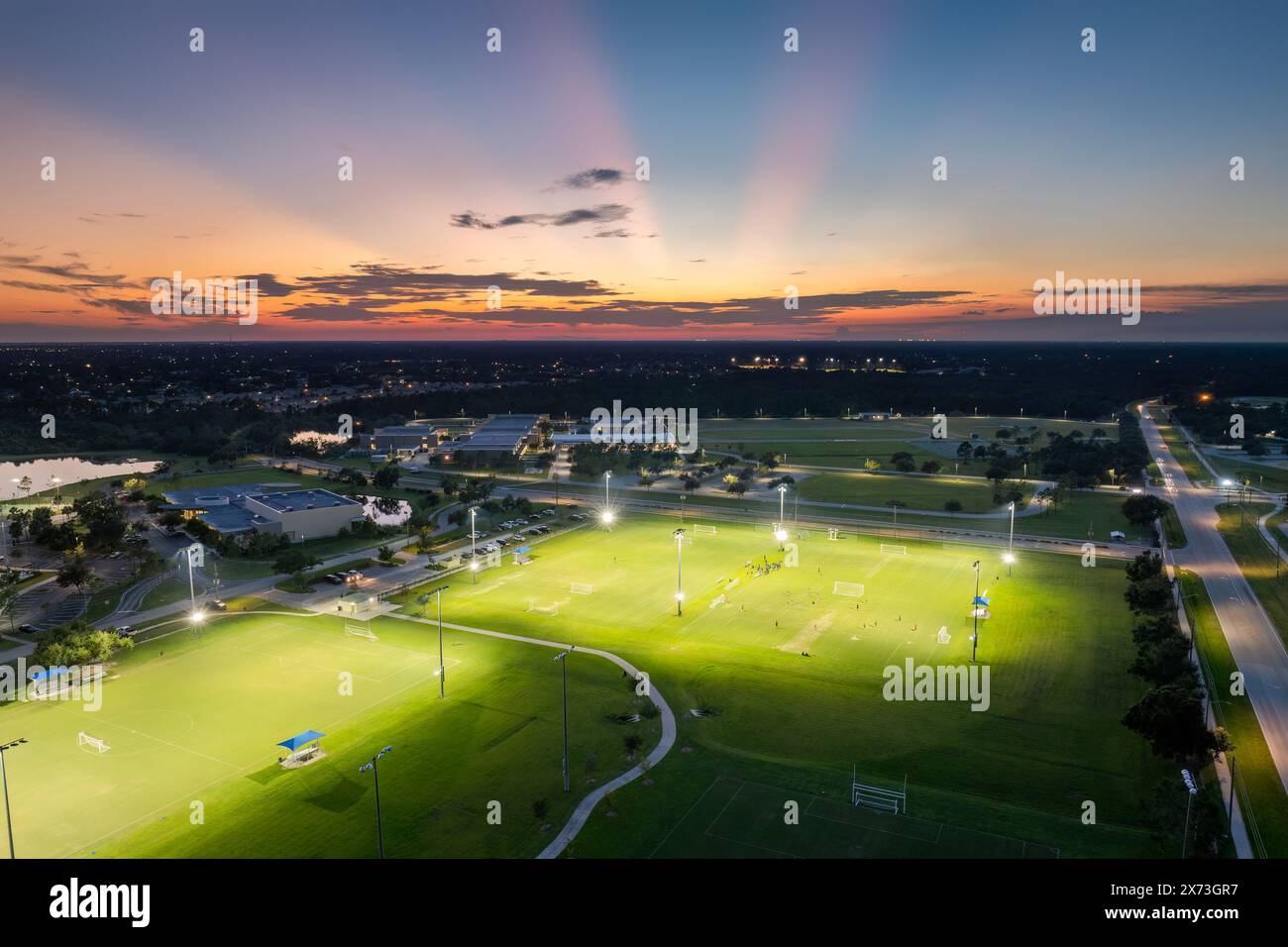 Public sports stadium with young people playing football game at sunset ...