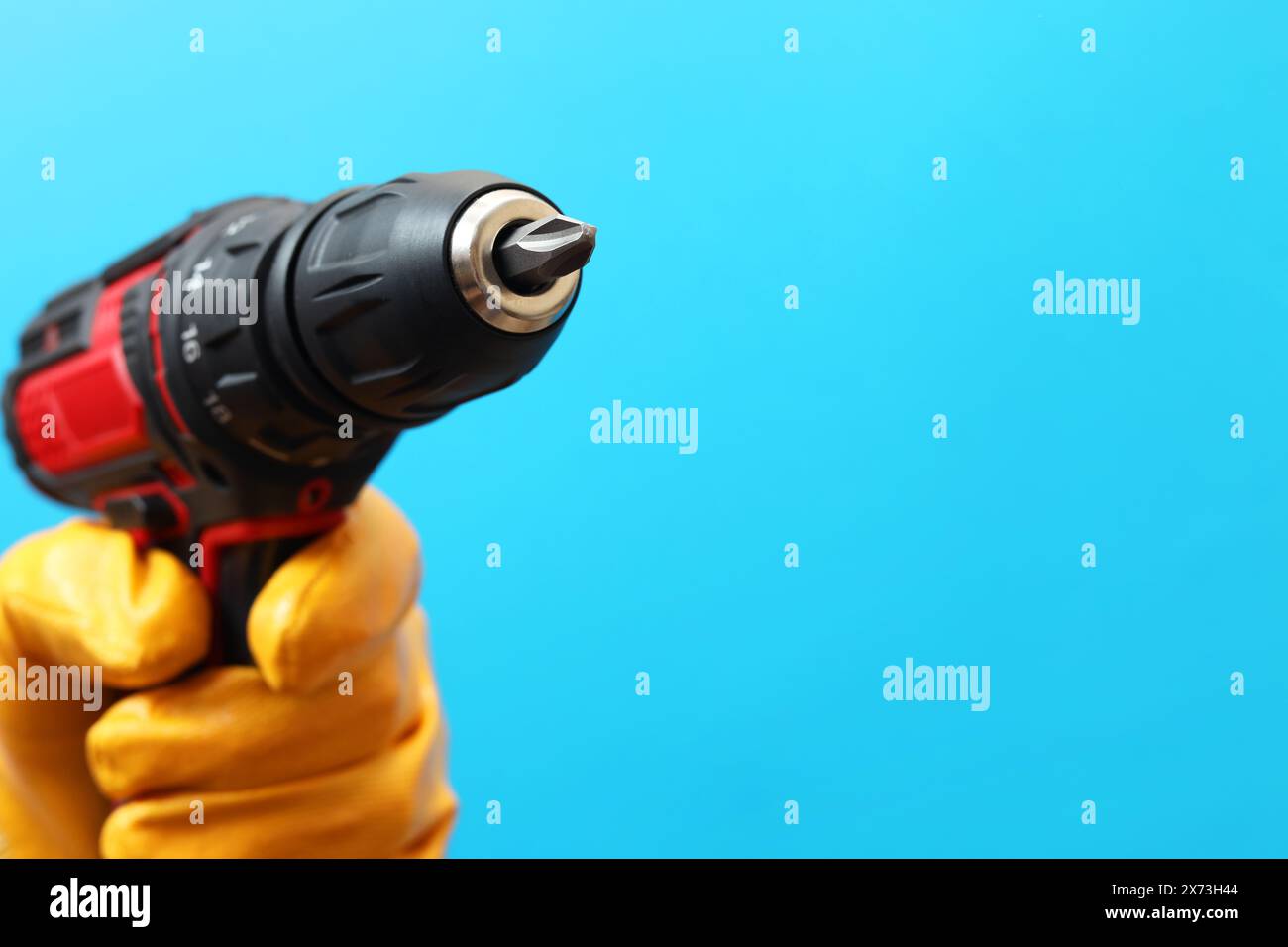 Handyman holding electric screwdriver on light blue background, closeup ...
