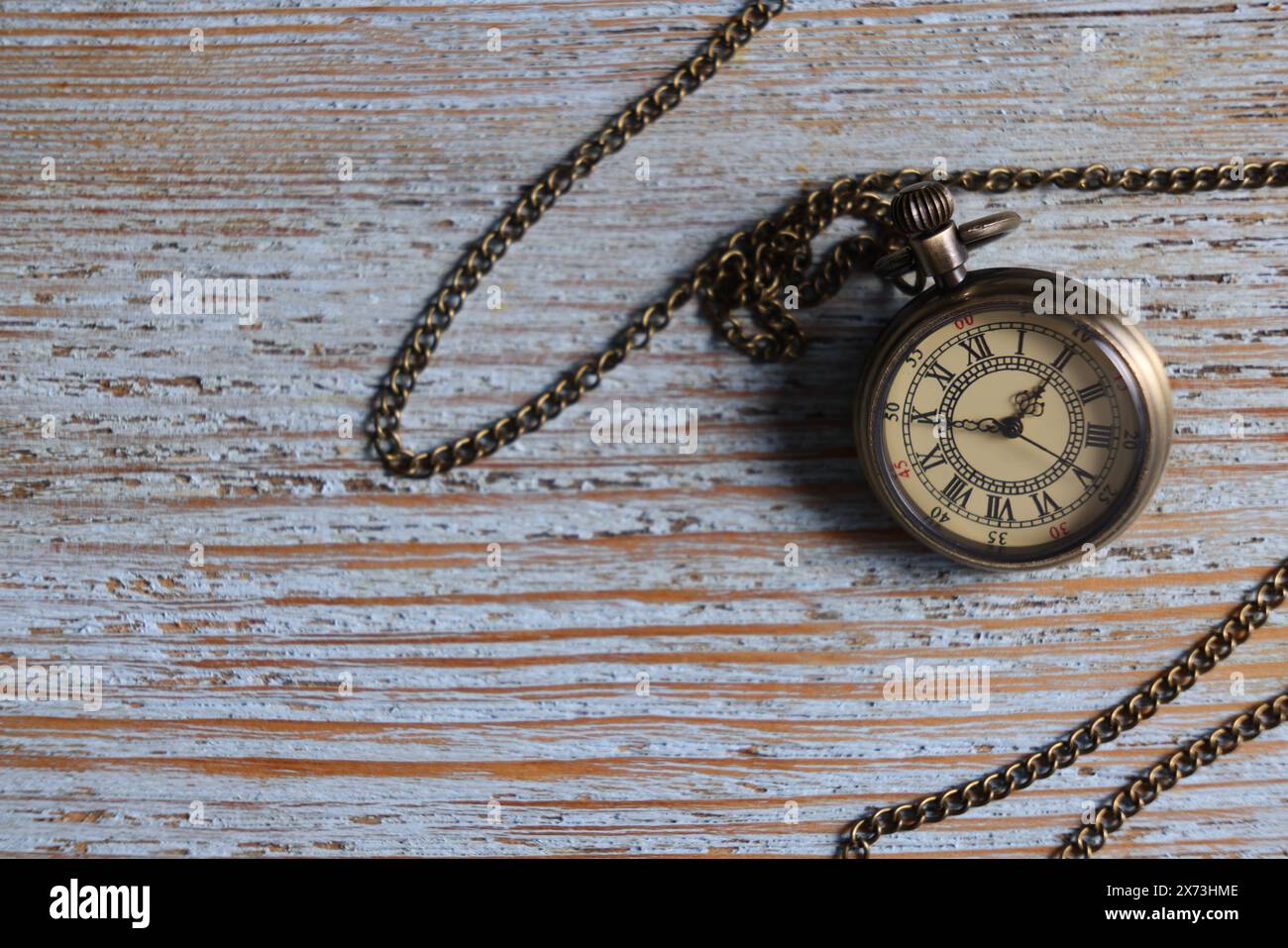 Pocket clock with chain on old wooden table, top view. Space for text ...