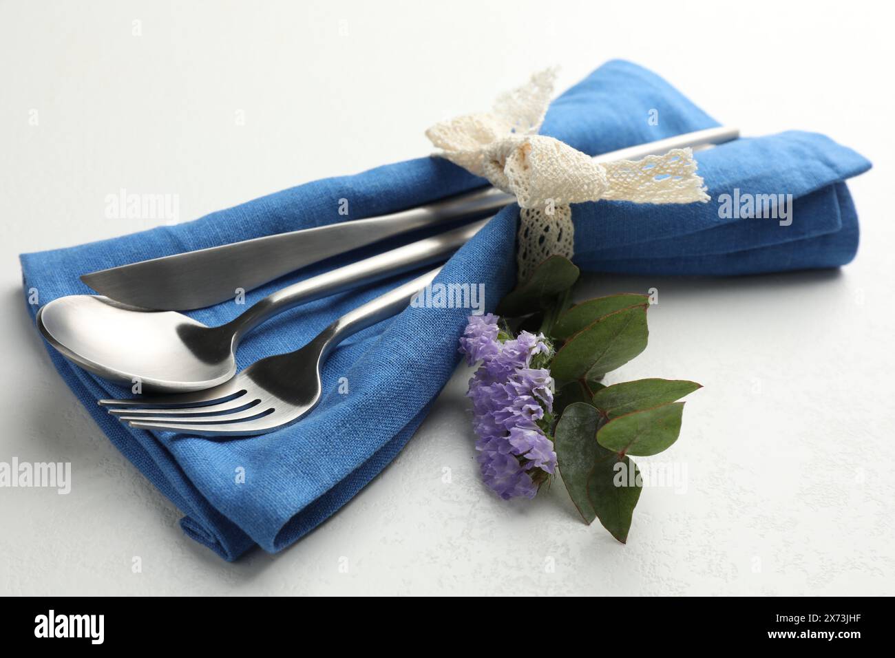 Stylish setting with cutlery and napkin on white textured table Stock ...