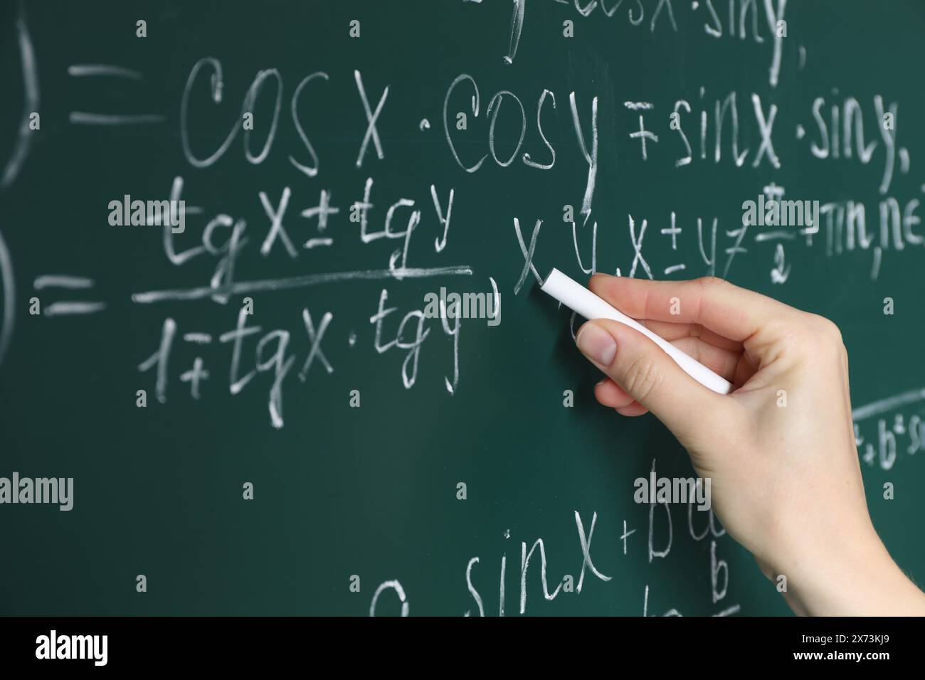 Teacher writing down math equation on green board, closeup Stock Photo ...