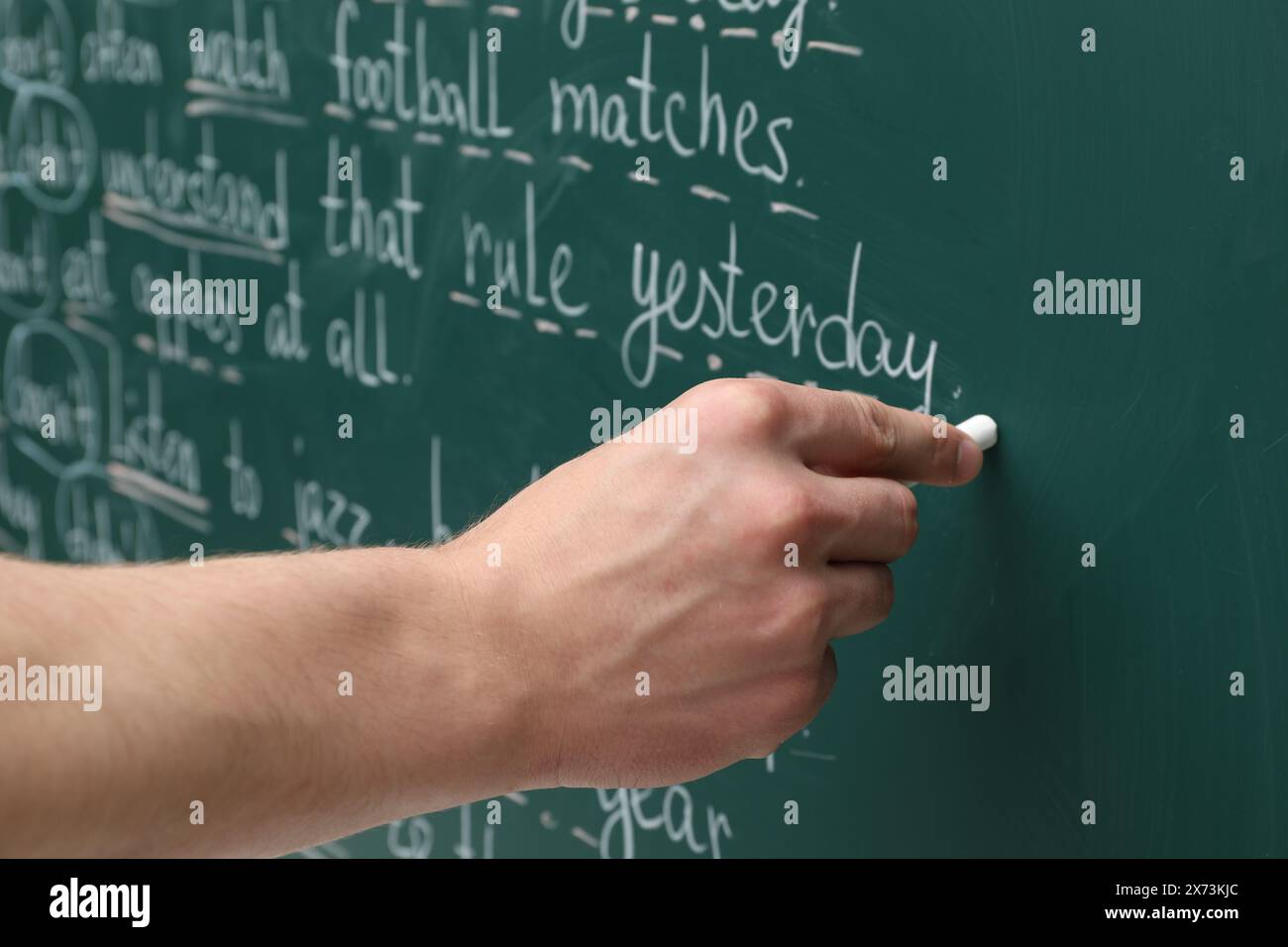 English teacher writing with chalk on green chalkboard, closeup Stock ...