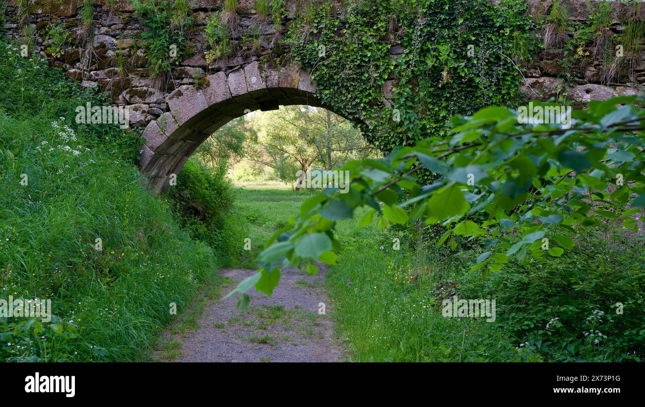 A shady stonebridge looking onto a sunny park Stock Photo - Alamy