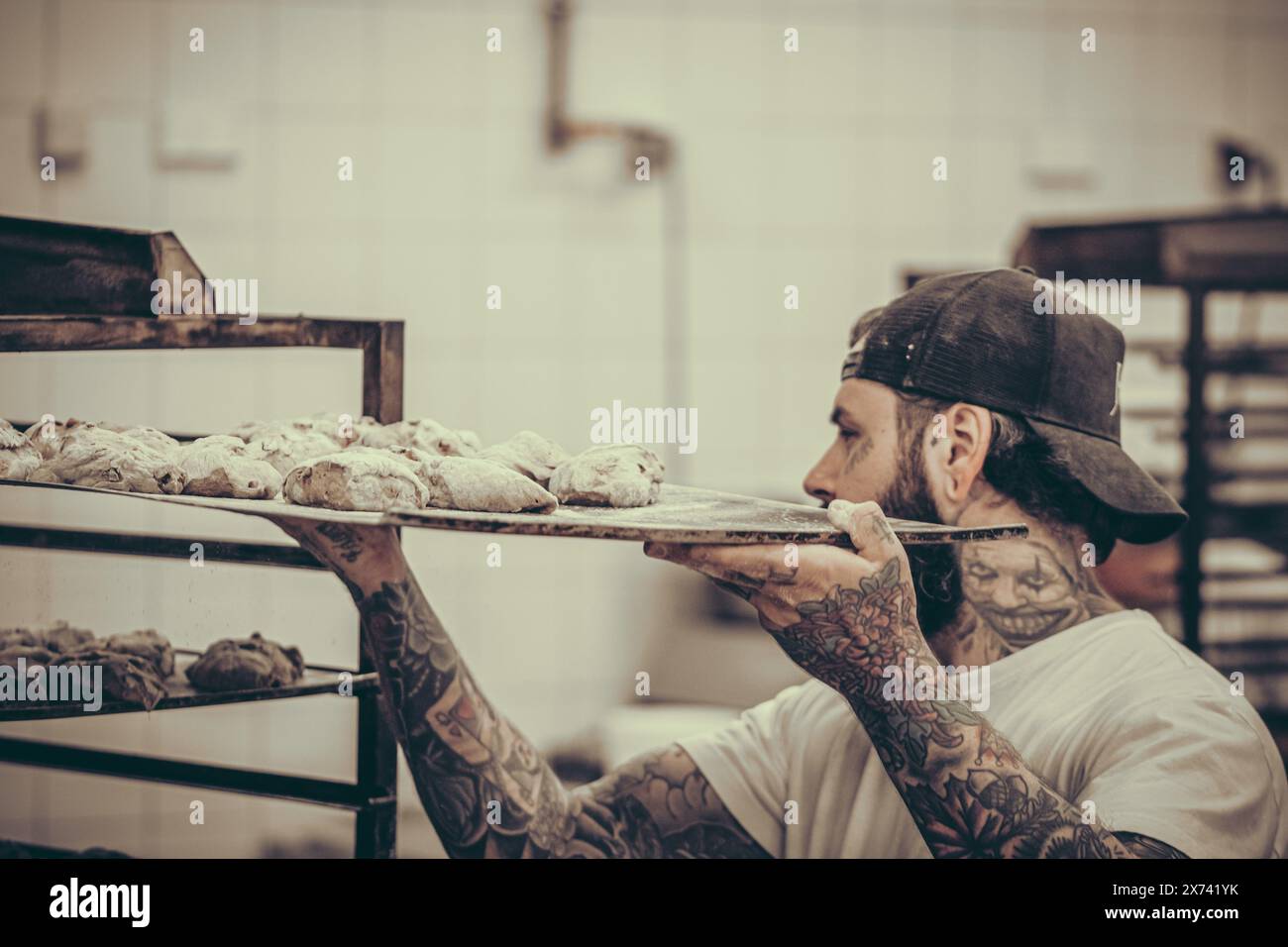 The baker pushes a tray of raw rolls of dough into a cart, vintage ...