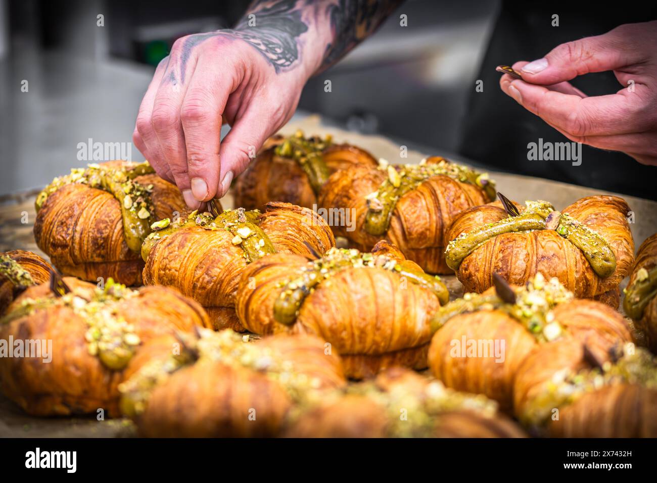 Confectioner's hand with tattoos decorating tartlets with chocolate ...