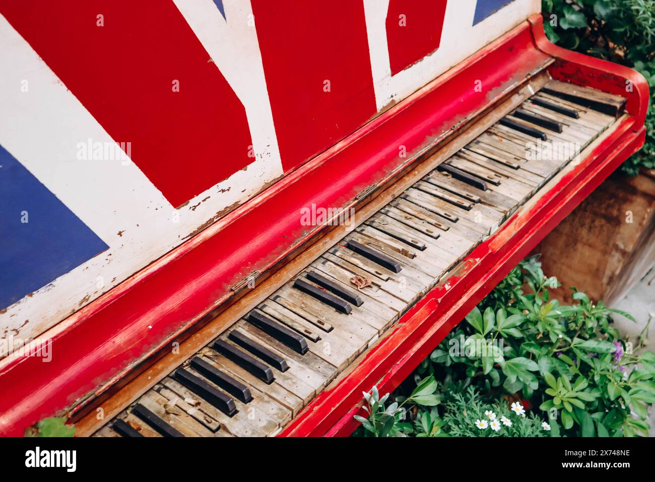 An old piano in the colors of the British flag with shabby keys on the ...