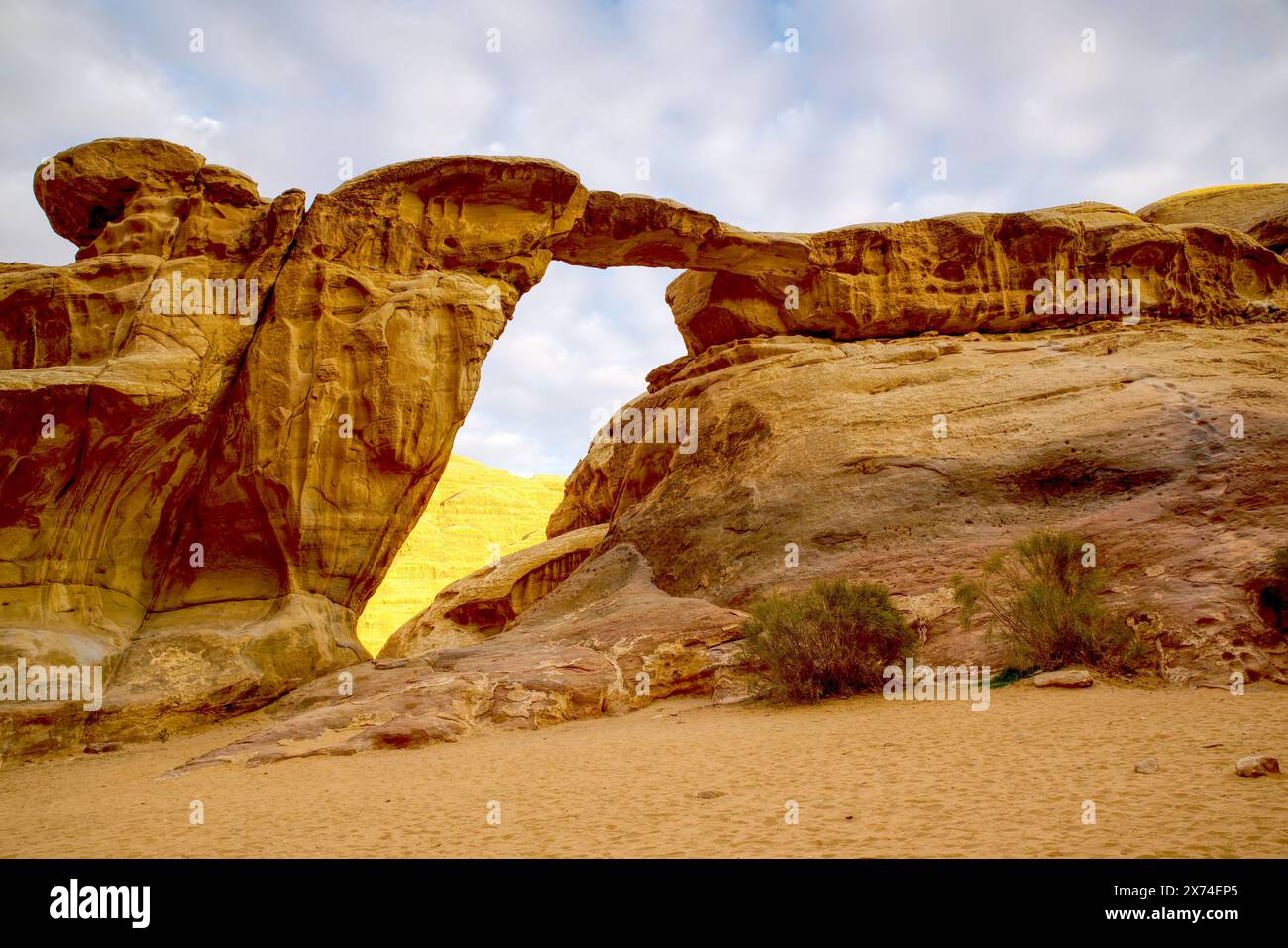 Wadi Rum Burdah Rock Bridge in Jordan with cloudy sky and golden ...