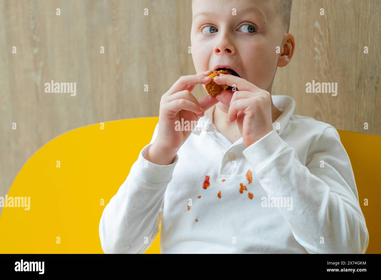 Dirty ketchup stains on white clothes. The child eating unhealthy fat ...