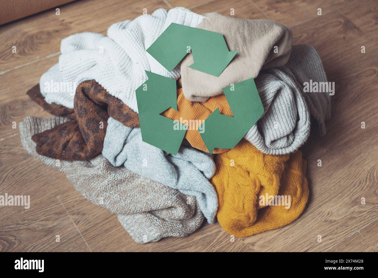 Pile of old autumn clothes on the floor home and recycle sign cut out ...