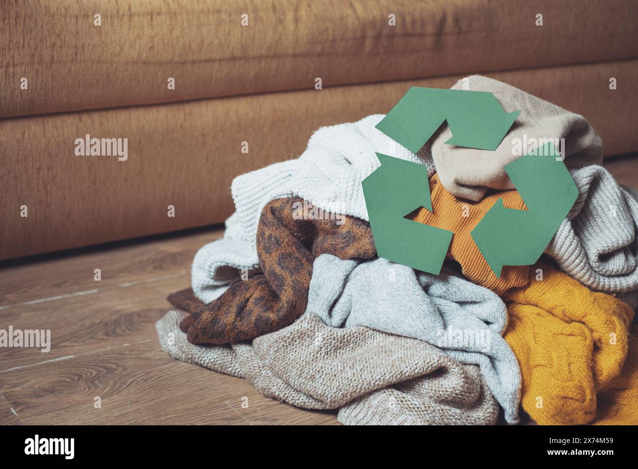 Pile of old autumn clothes on the floor home and recycle sign cut out ...