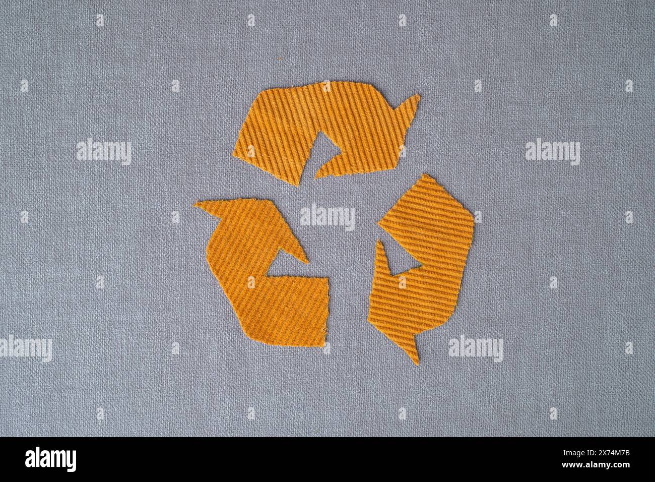 Recycling sign made yellow old clothing of corduroy on gray upholstery ...