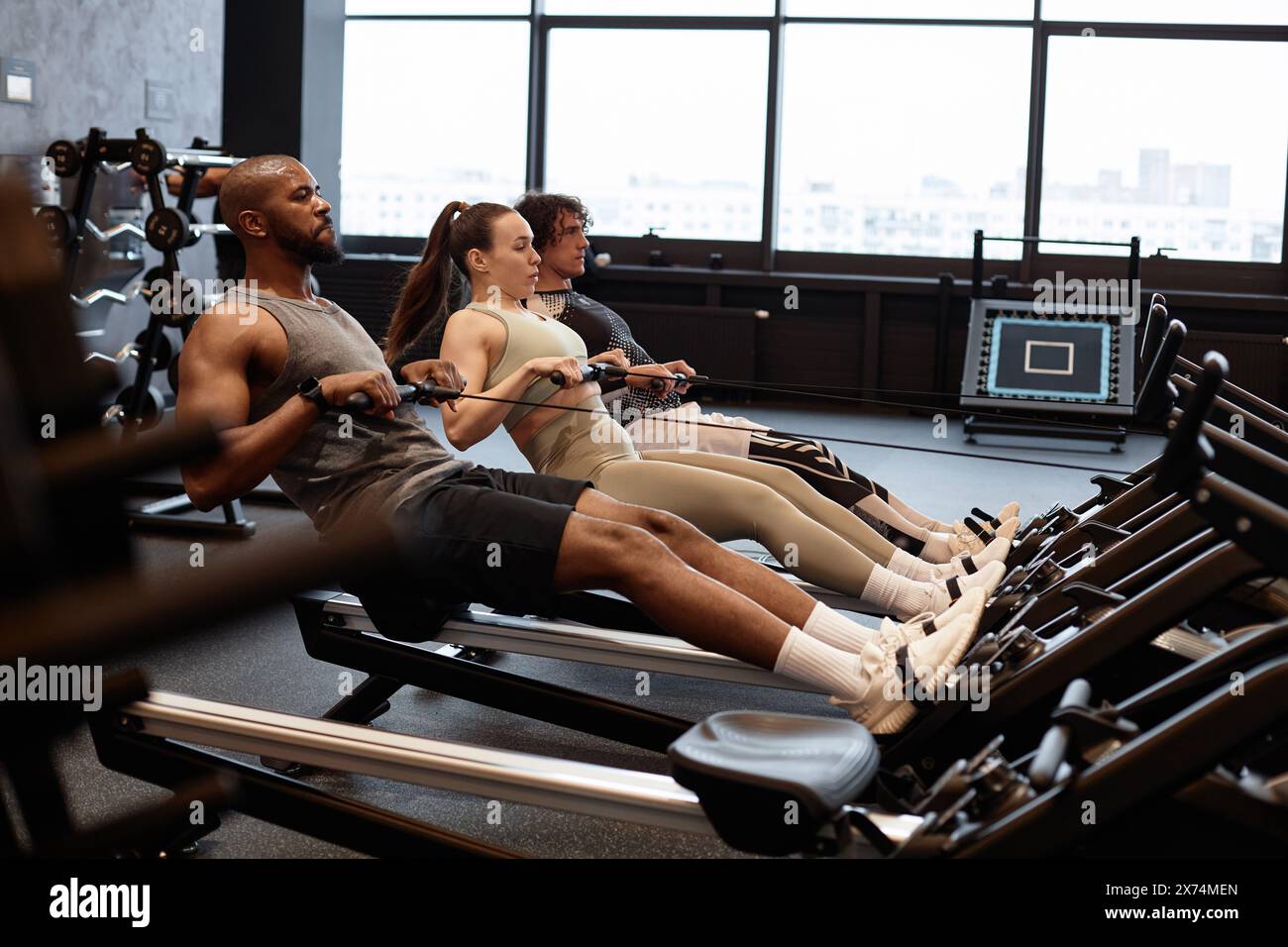 Side view portrait of people using rowing machine during strength ...