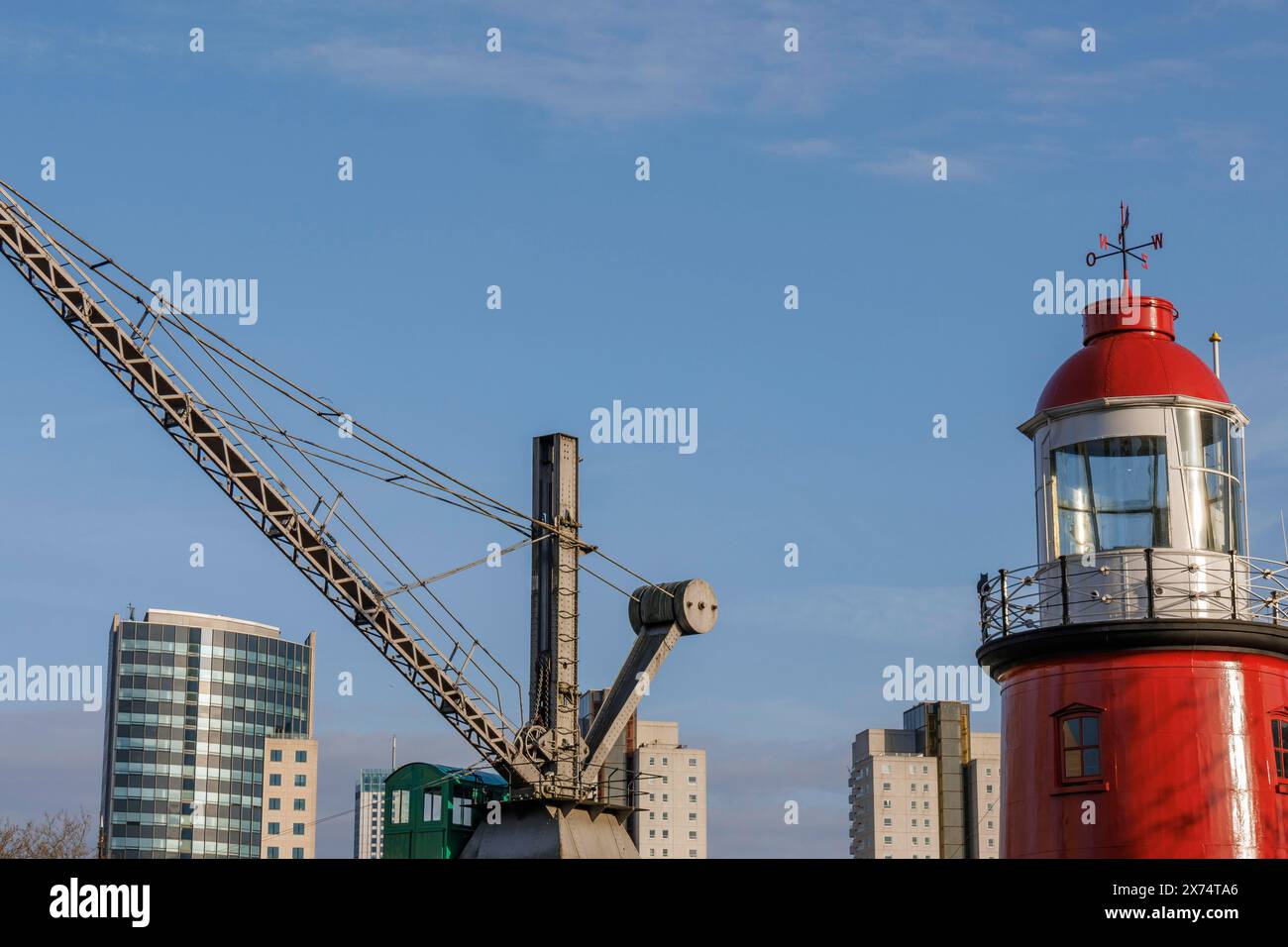A red lighthouse and a crane are visible in front of modern skyscrapers ...