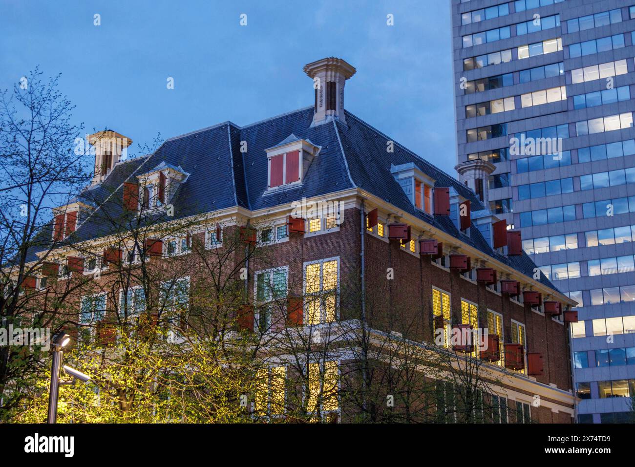 Historic illuminated building next to a modern skyscraper at sunset ...