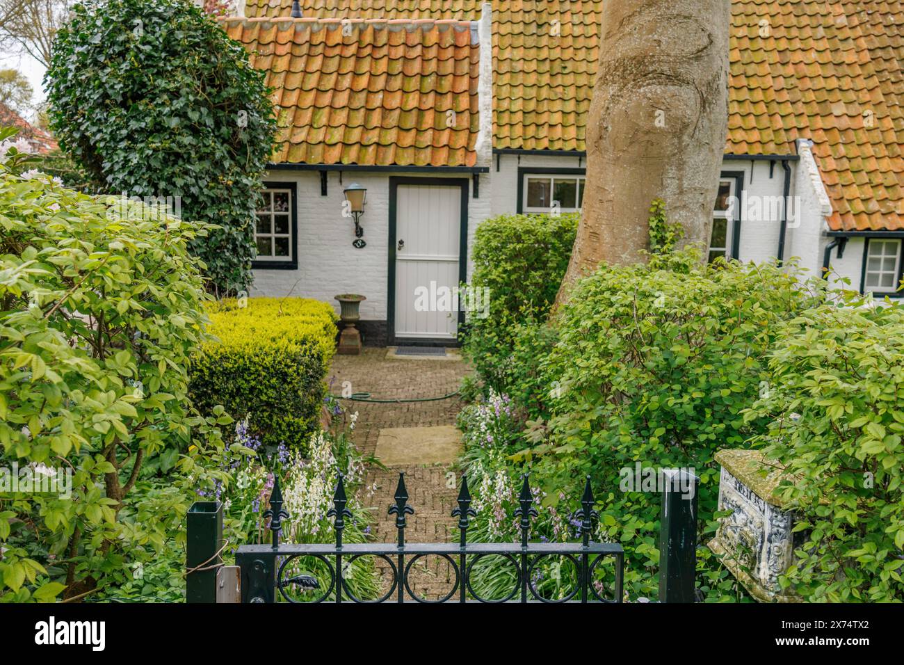 Charming house with garden and red tiled roof, surrounded by bushes ...