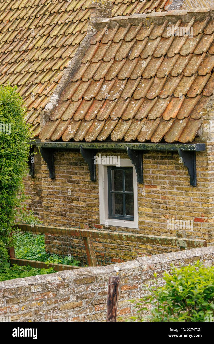 Small brick house with rustic tiled roof and surrounded by fresh green ...