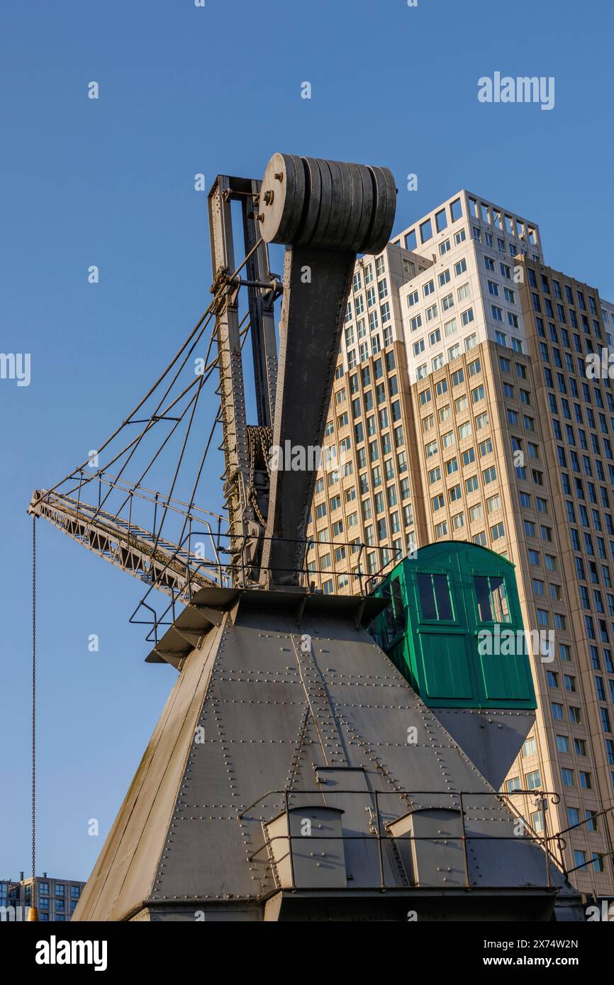 Steel crane in front of a modern skyscraper and blue sky, small harbour ...