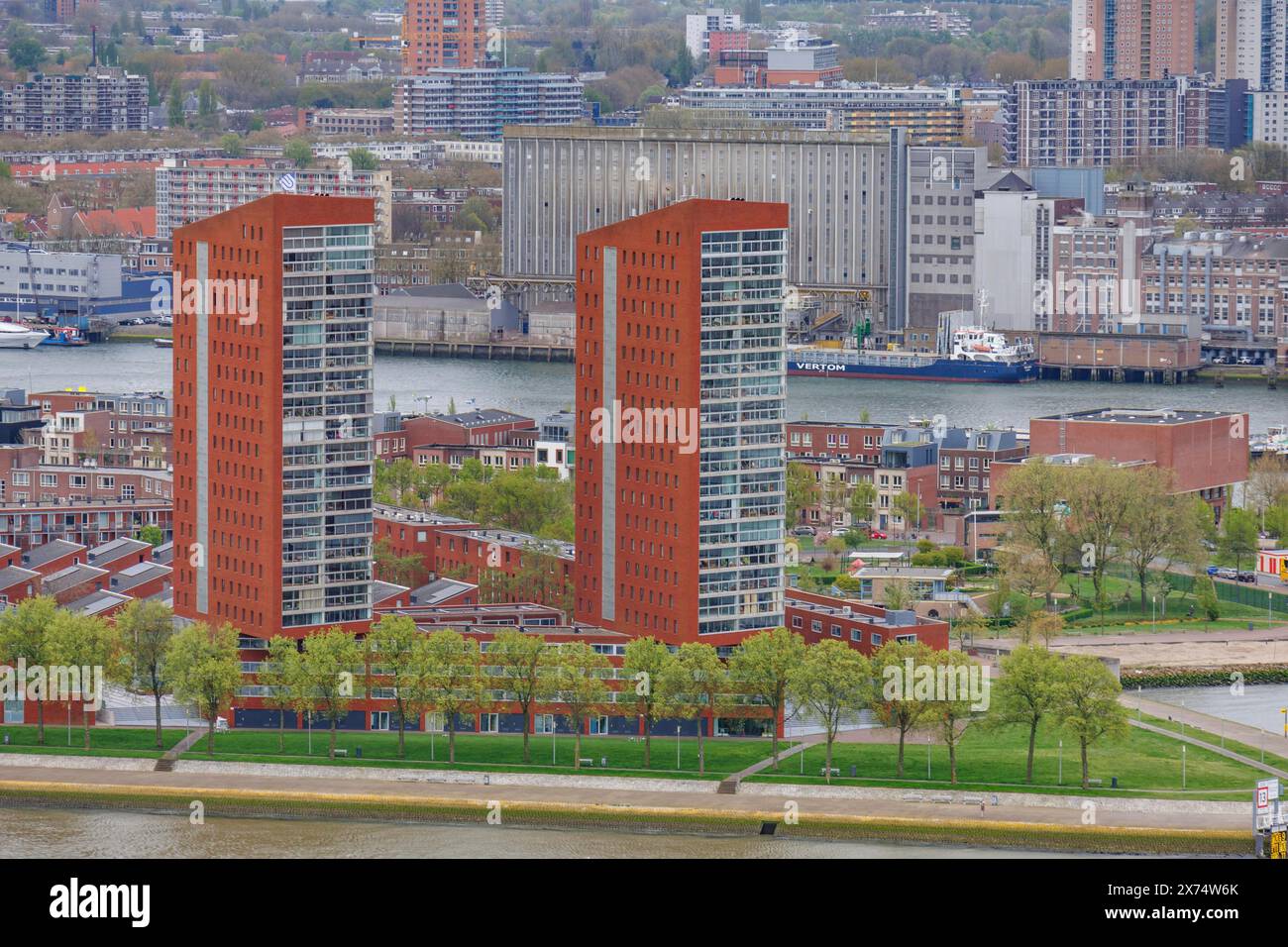Urban landscape with striking red skyscrapers, a river and green trees ...