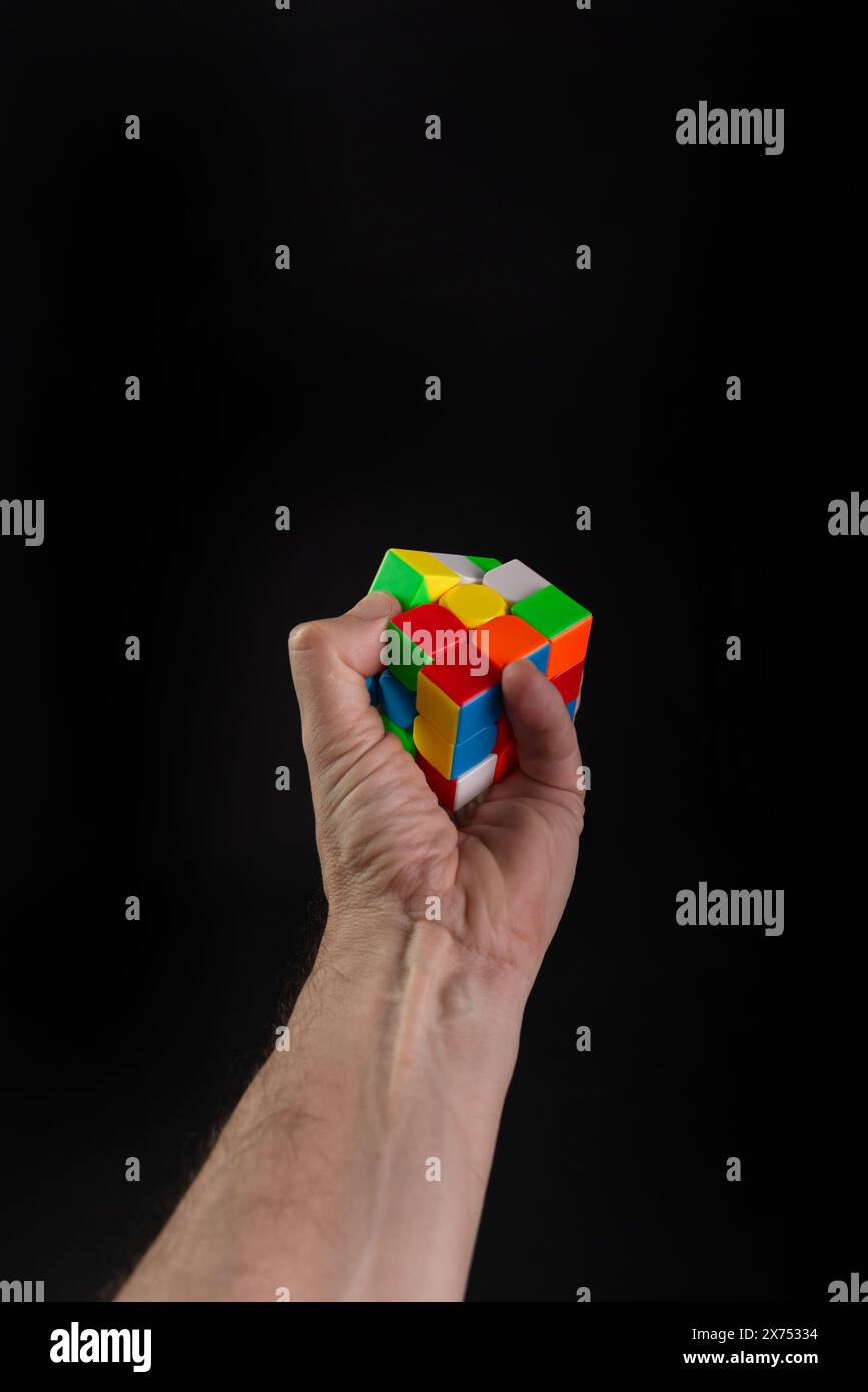 Salvador, Bahia, Brazil - May 15, 2024: Rubiks cube in a persons hands, portrait, black ...