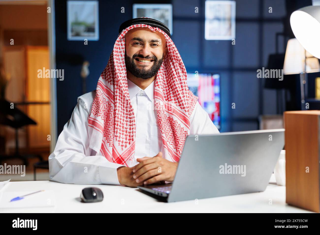 Male person dressed in traditional Arabic clothing is seated with his ...