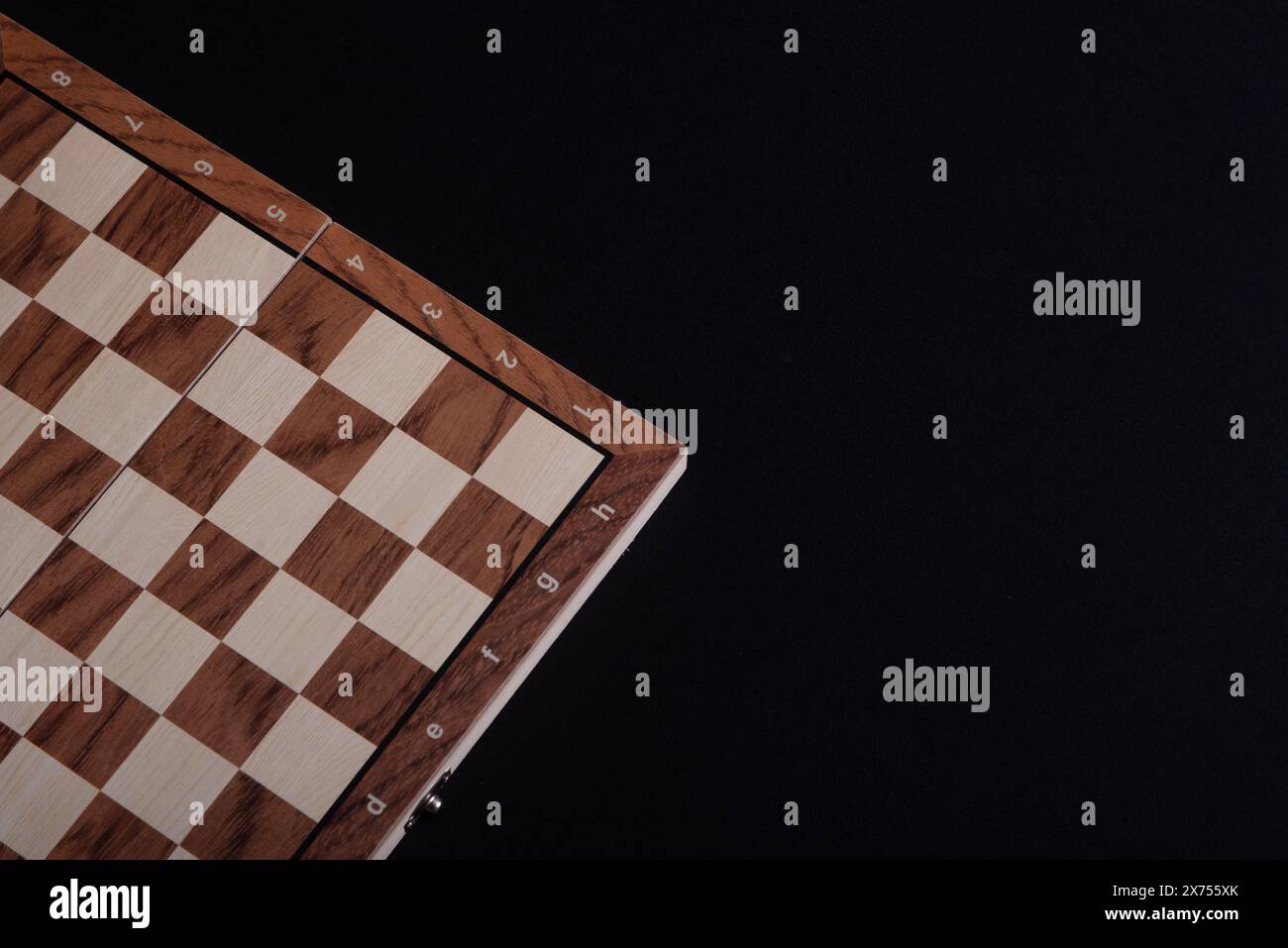 Part of an empty wooden checkers or chess board on a black background ...