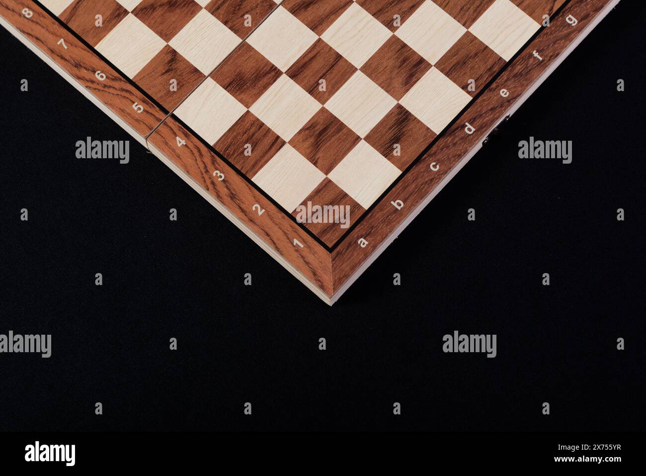 Part of an empty wooden checkers or chess board on a black background ...