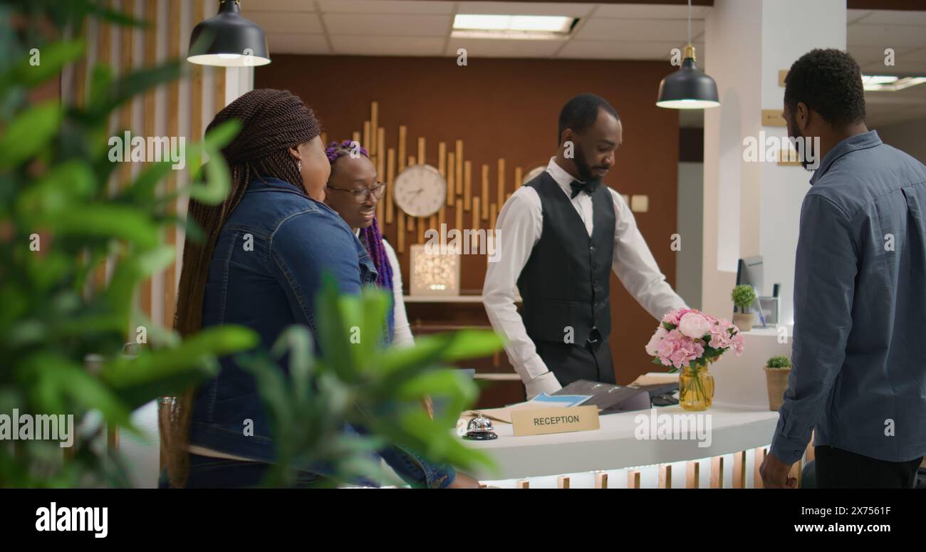 Receptionist doing check in for guests, helping travellers to relax ...