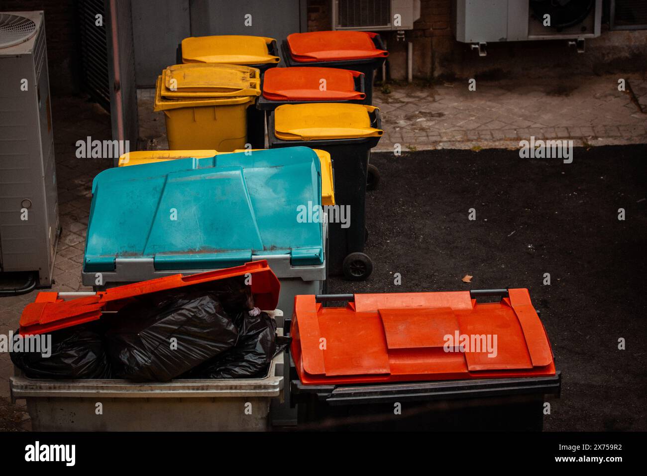 Colorful bright dumpsters for sorting miscellaneous waste in a back ...