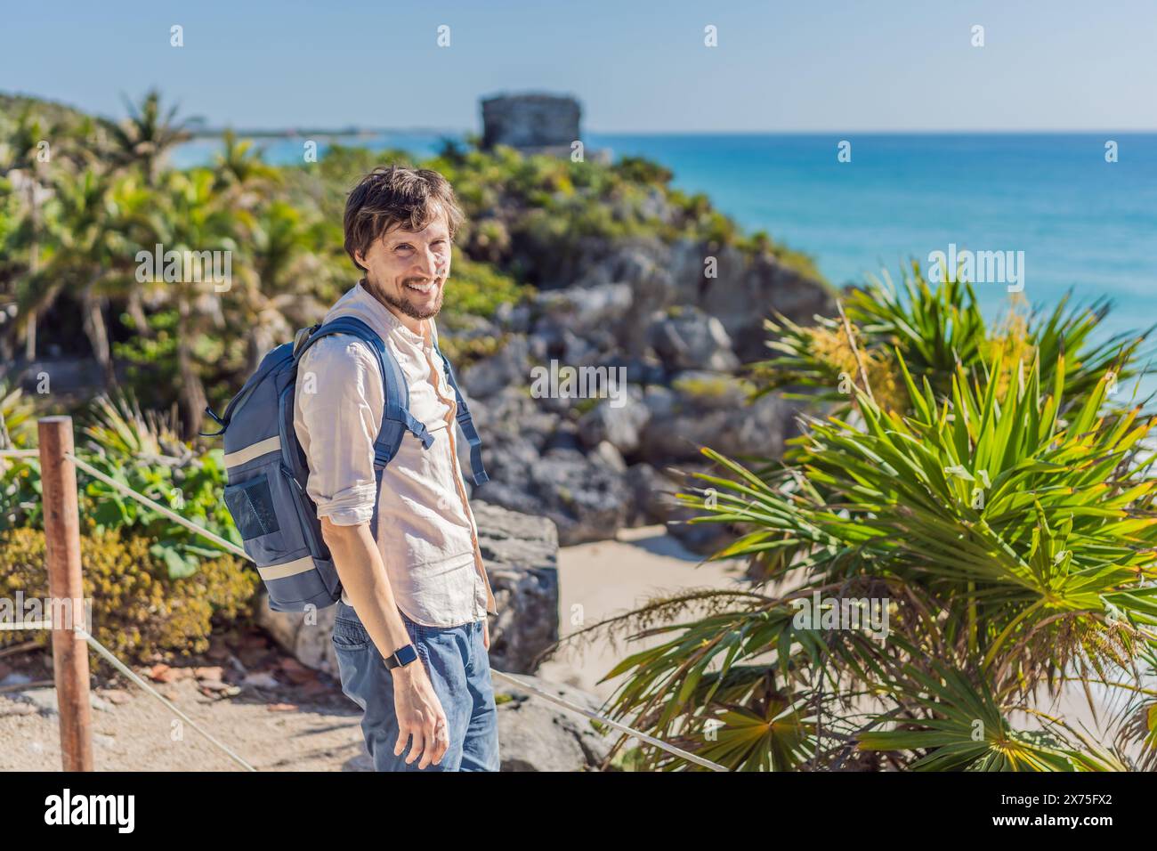 Man tourist enjoying the view Pre-Columbian Mayan walled city of Tulum ...