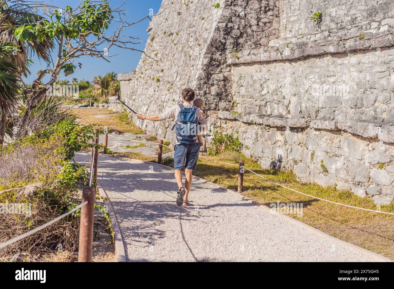 Father and son tourists enjoying the view Pre-Columbian Mayan walled ...