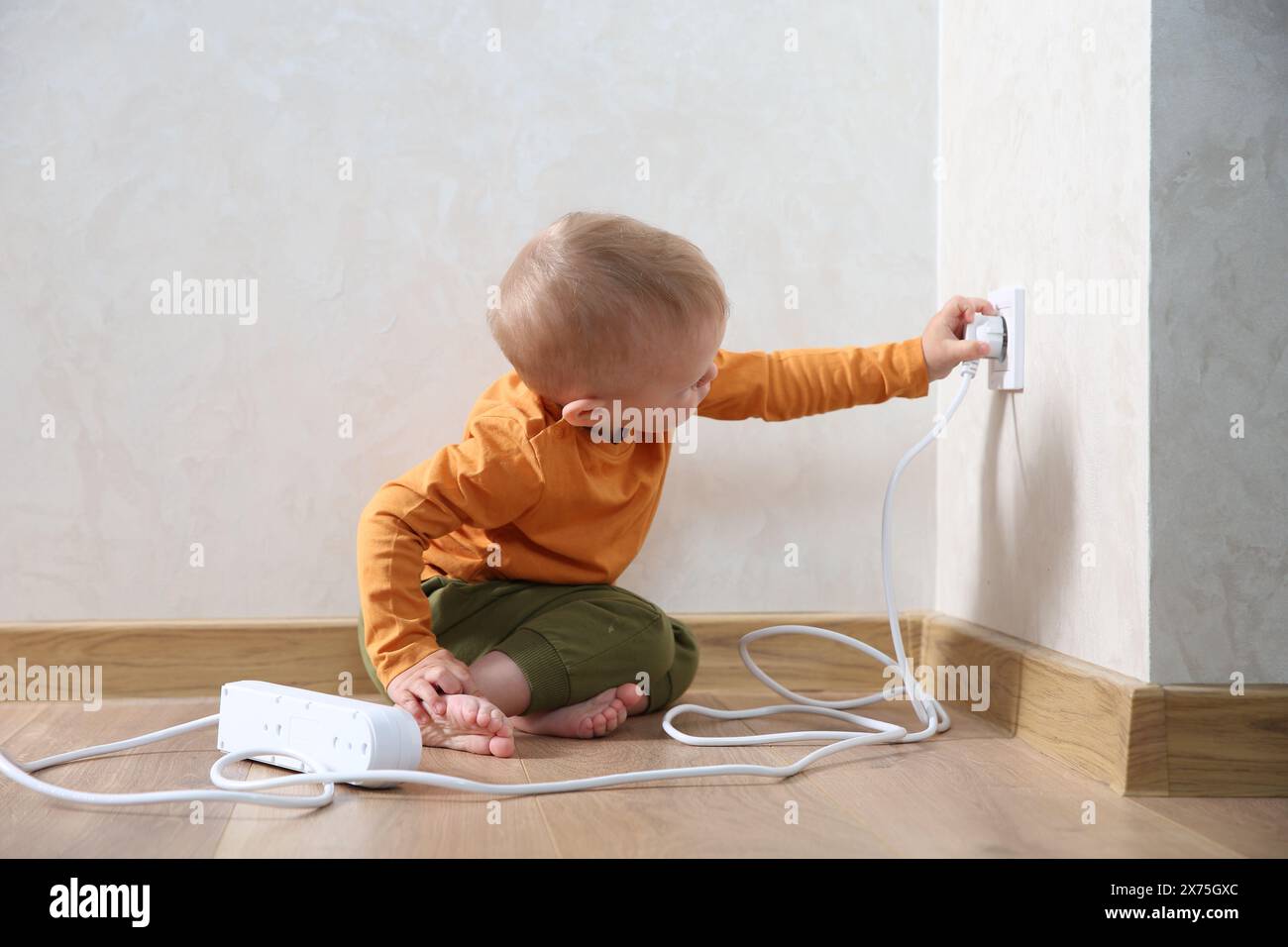 Little child playing with electrical socket and power strip plug at ...
