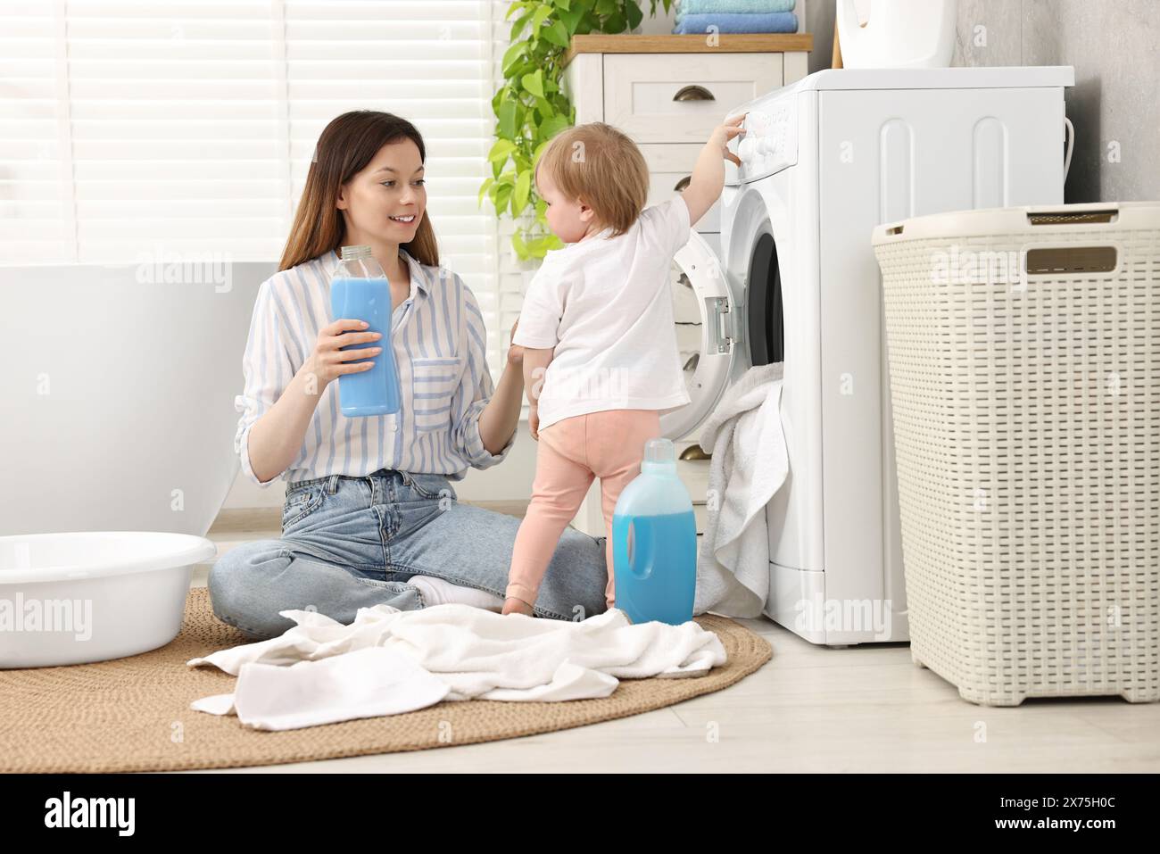 Happy mother with her daughter washing baby clothes in bathroom Stock ...