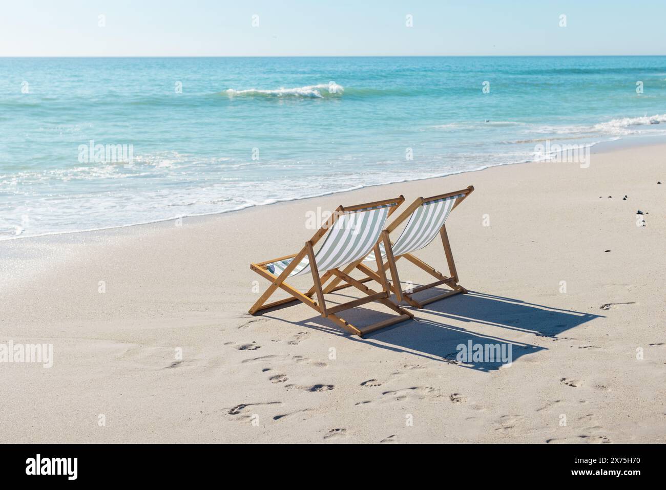 At beach, two empty chairs facing ocean on sandy beach Stock Photo - Alamy