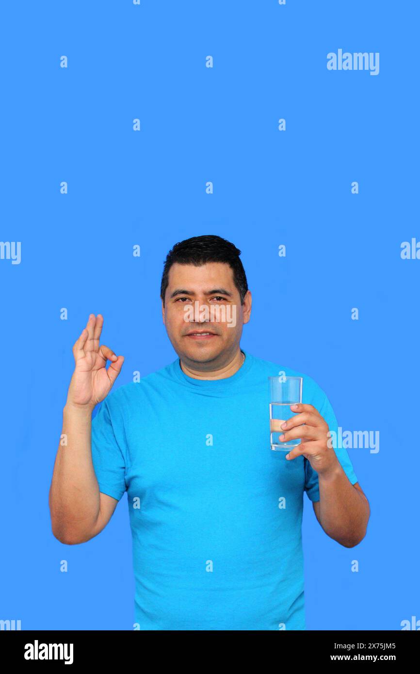 Dark-skinned Latino adult man shows his glass with still water to ...