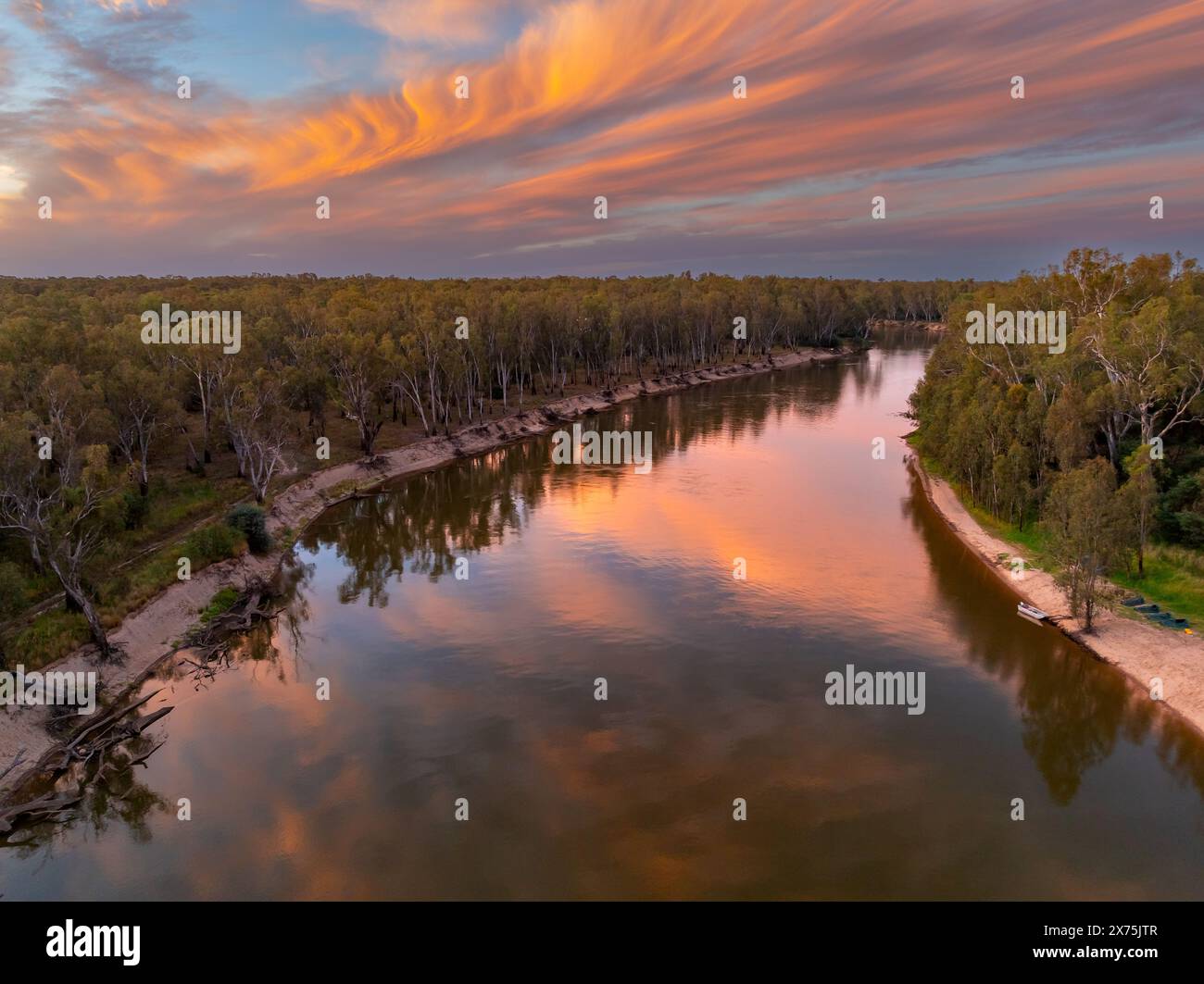 Aerial view of a wide inland river under a colourful sunset sky on the ...