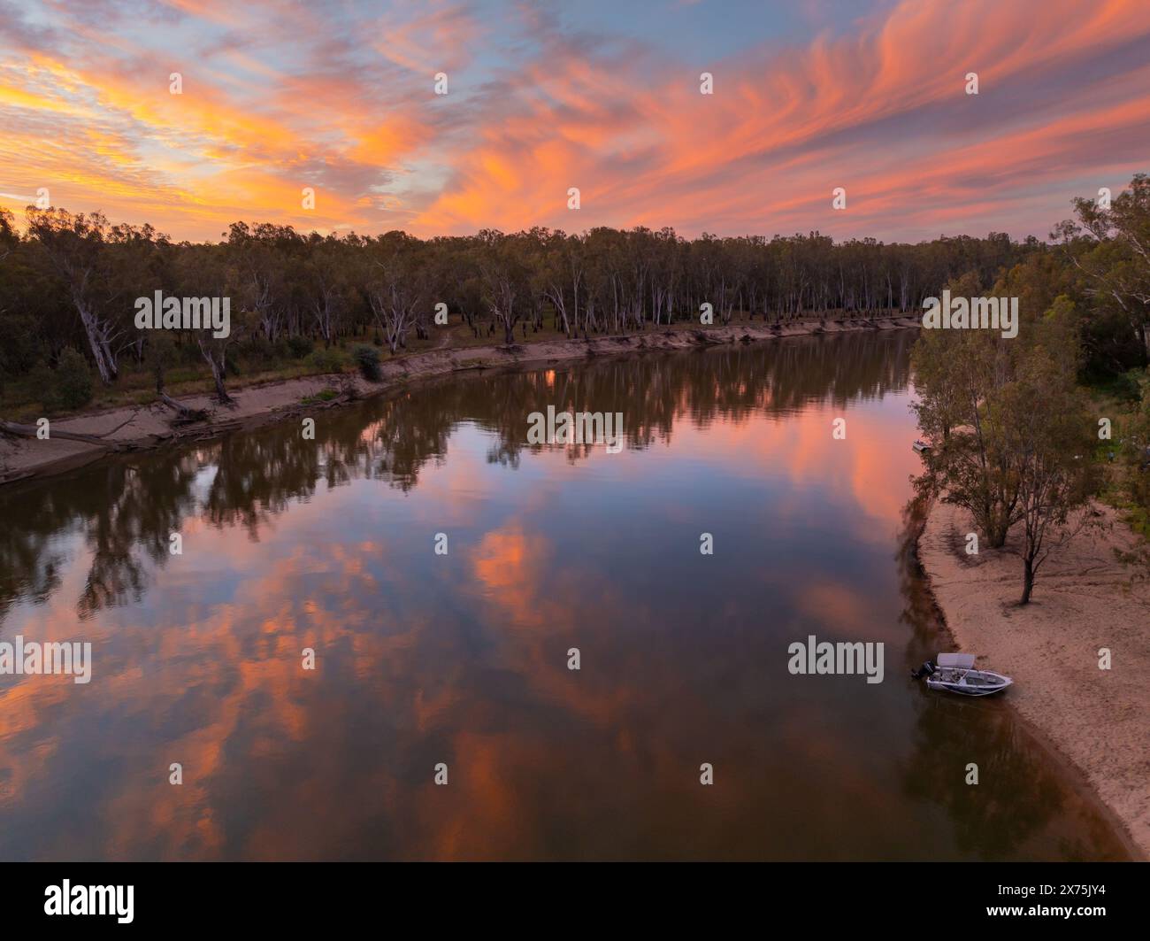 Aerial view of a wide inland river under a colourful sunset sky on the ...