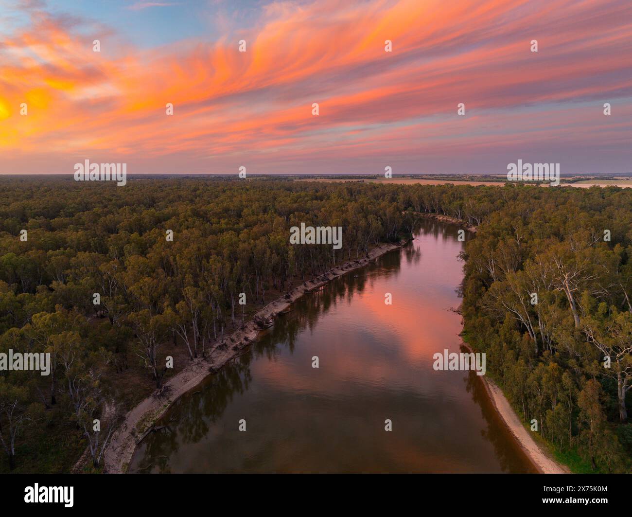 Aerial view of a wide inland river under a colourful sunset sky on the ...