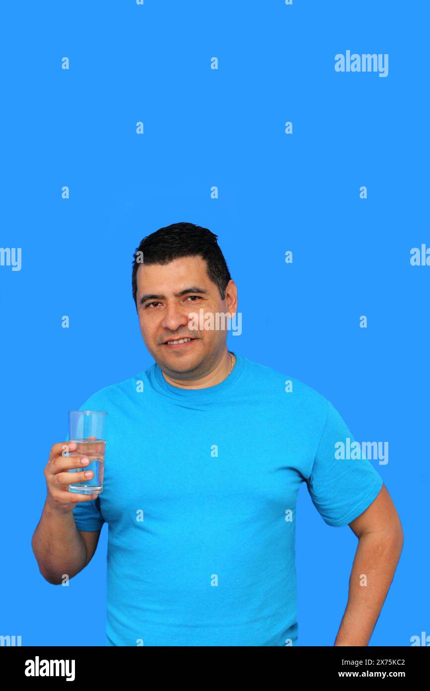 Dark-skinned Latino adult man shows his glass with still water to ...