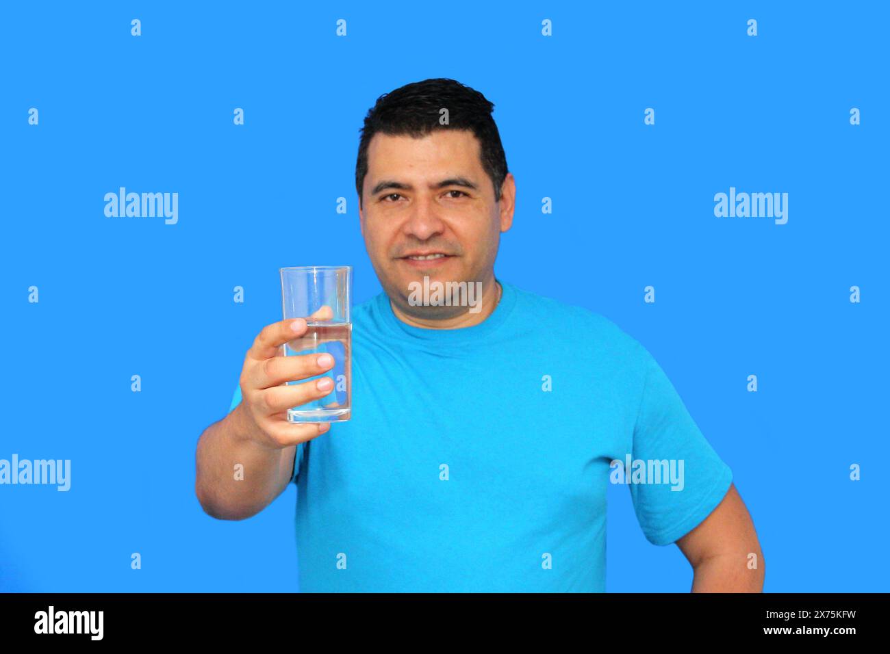 Dark-skinned Latino adult man shows his glass with still water to ...
